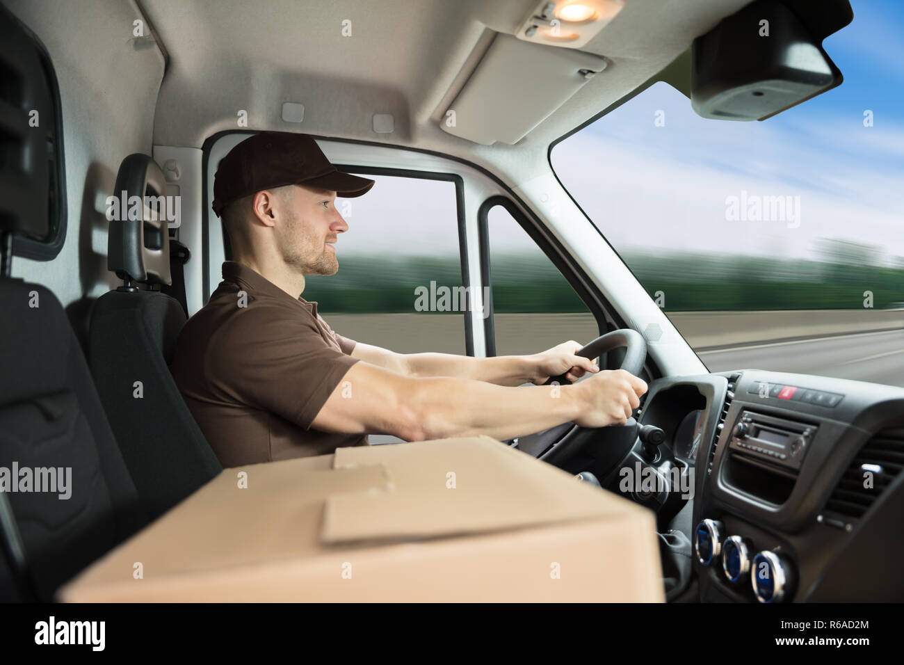 Delivery Man Sitting Inside Van With Cardboard Box Stock Photo - Alamy