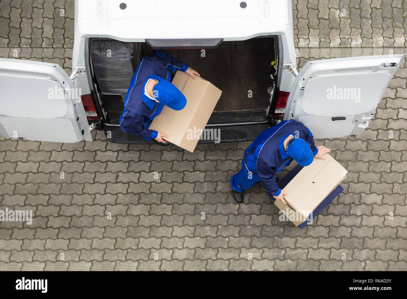 Two Delivery Men Unloading Cardboard Box From Truck Stock Photo - Alamy