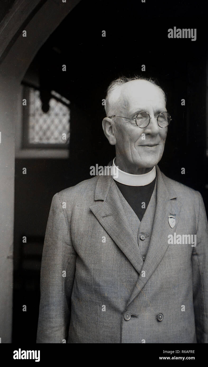 1950s, historical, an elderly Parish priest standing at the entrance to ...