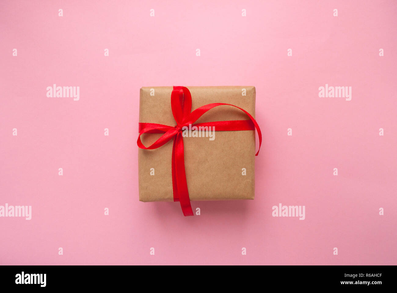 Gift box wrapped in brown colored craft paper and tied with red bow on ...