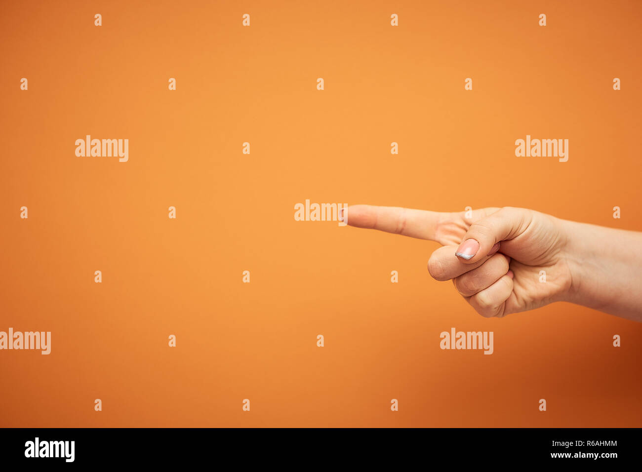 gesture, female index finger shows in side isolated on orange ...