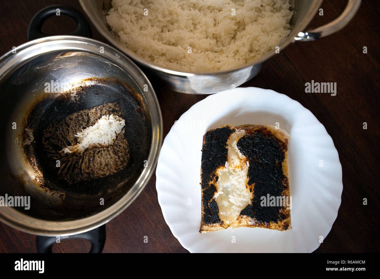 Completely burnt rice on plate next to pot standing on table in kitchen ...