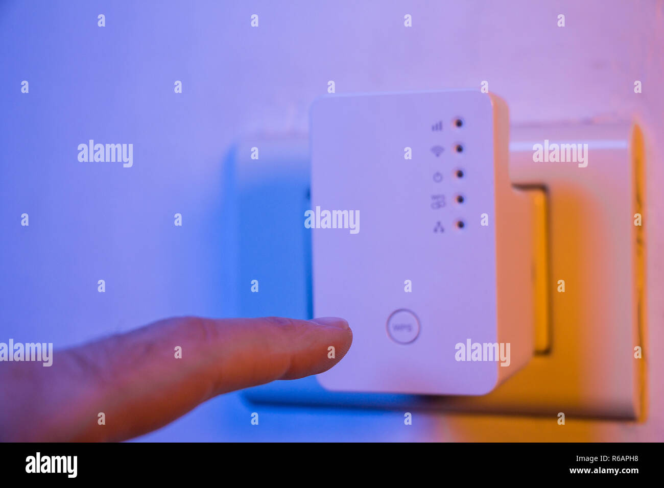 Man press with his finger on WPS button on WiFi repeater which is in ...