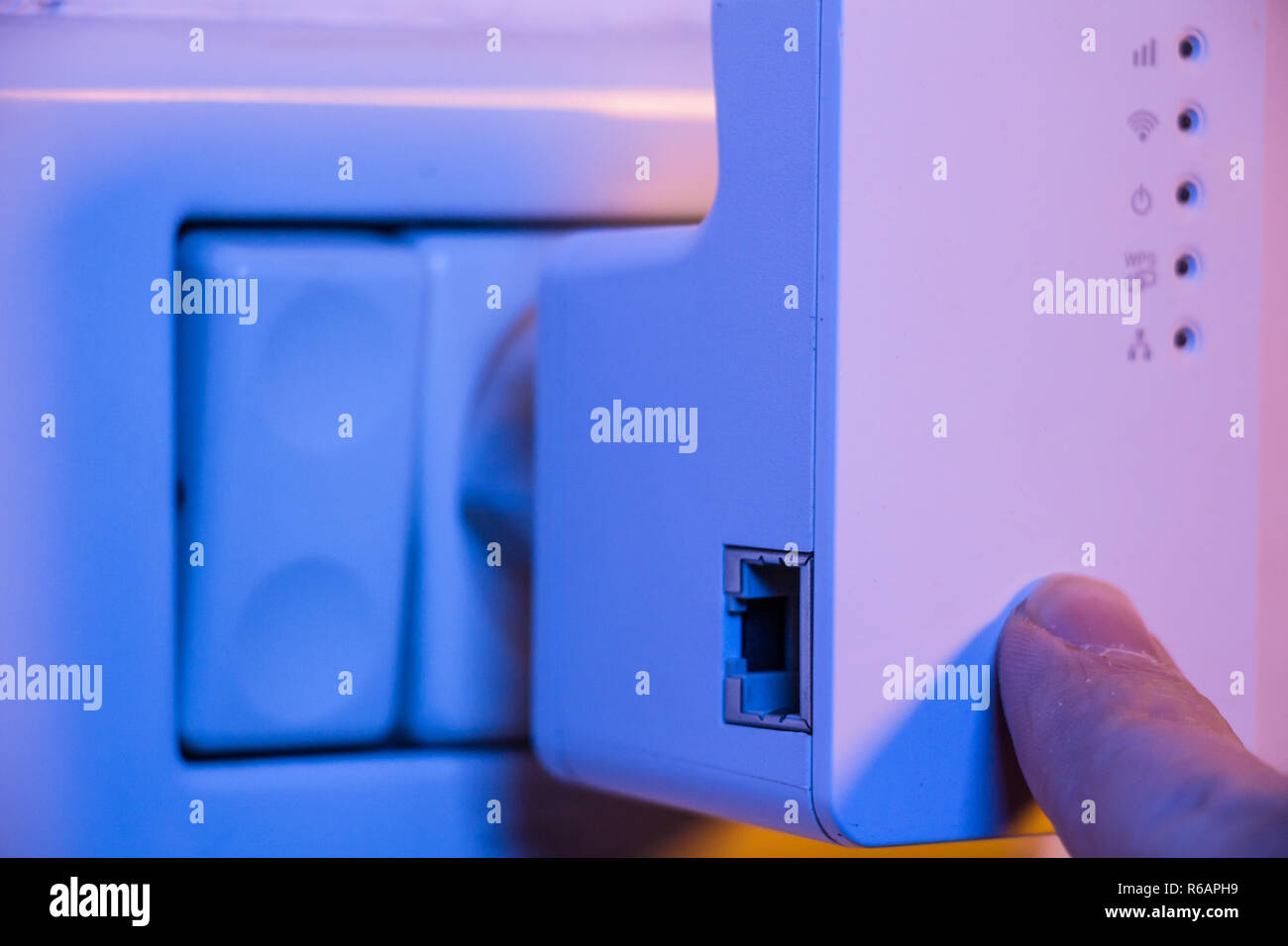 Man press with his finger on WPS button on WiFi repeater which is in ...