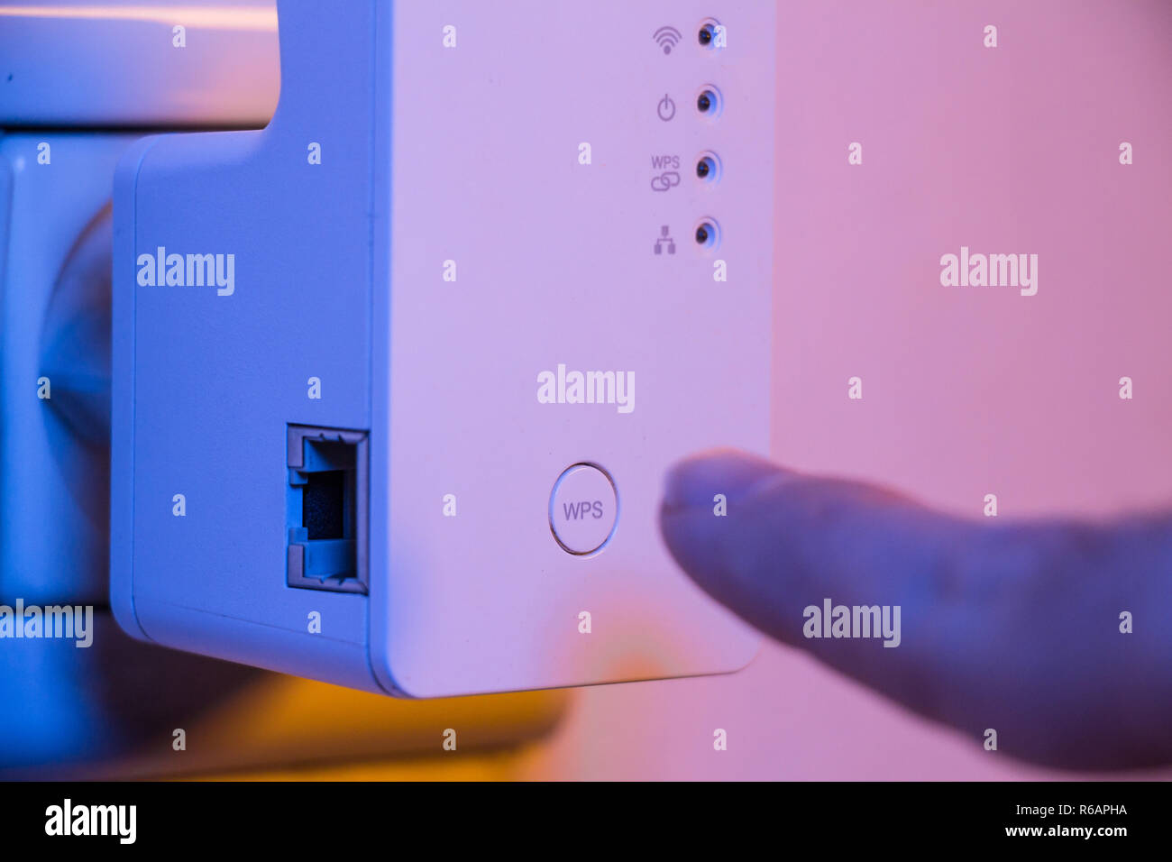 Man press with his finger on WPS button on WiFi repeater which is in ...