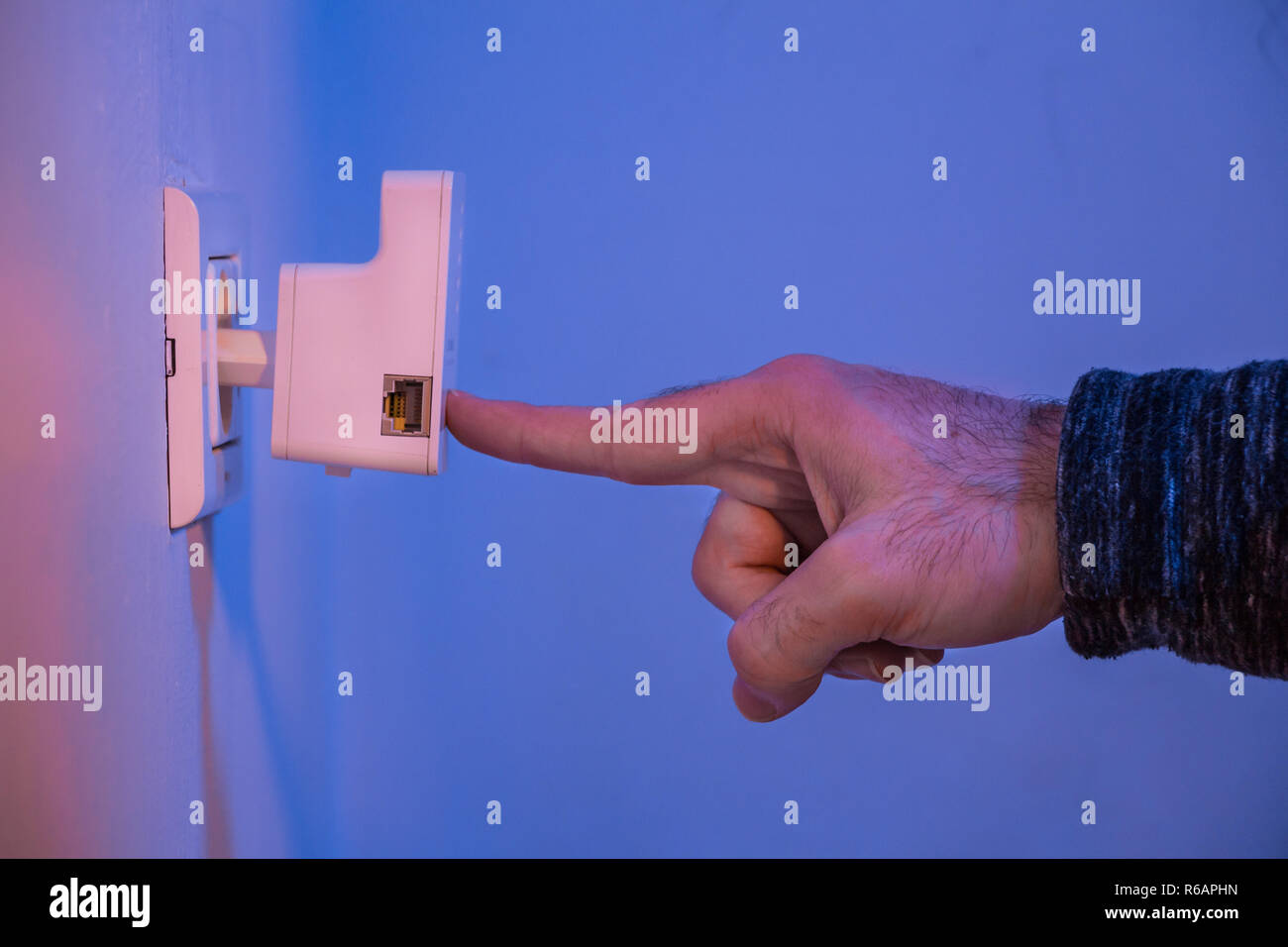 Man press with his finger on WPS button on WiFi repeater which is in ...