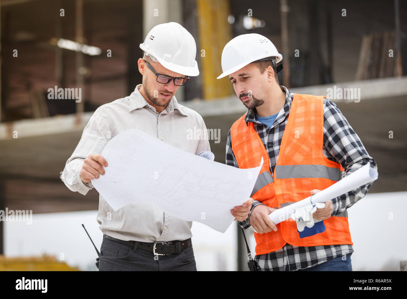 Male architect and developer discussing blueprints of an architect ...