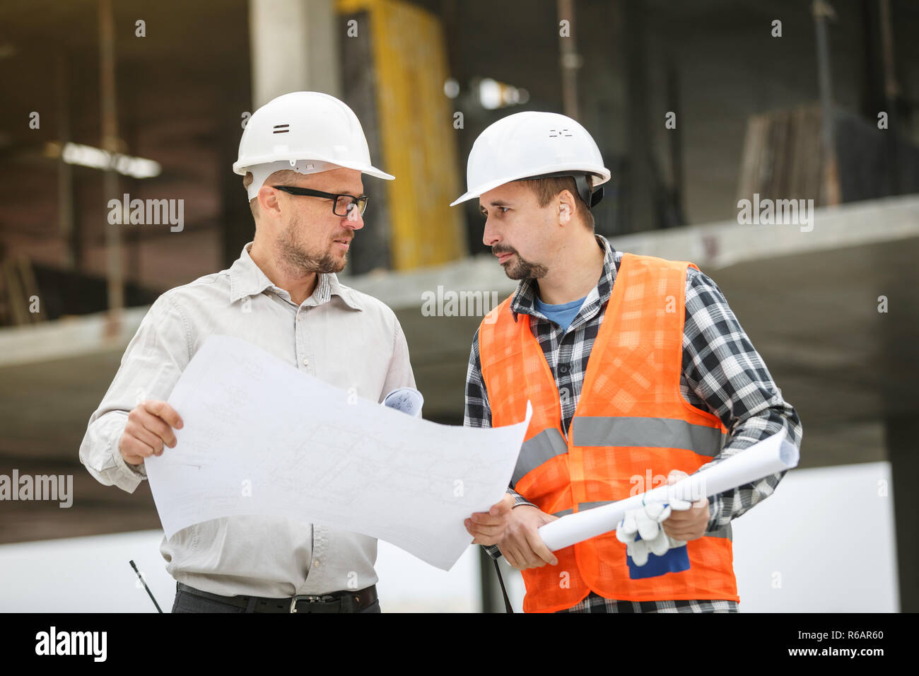Male architect and developer discussing blueprints of an architect ...