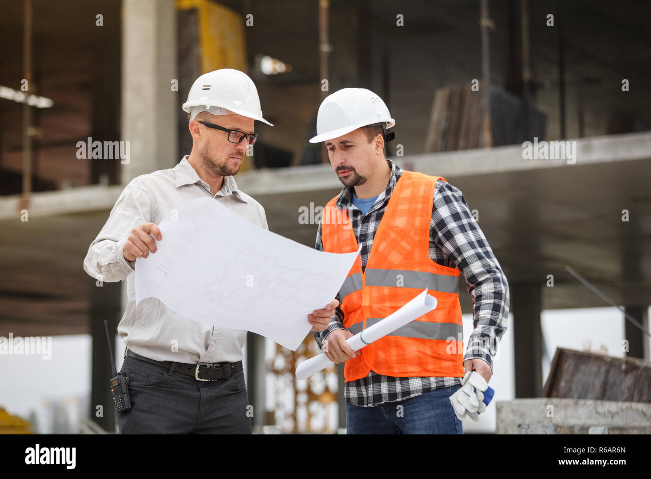 Male architect and developer discussing blueprints of an architect ...