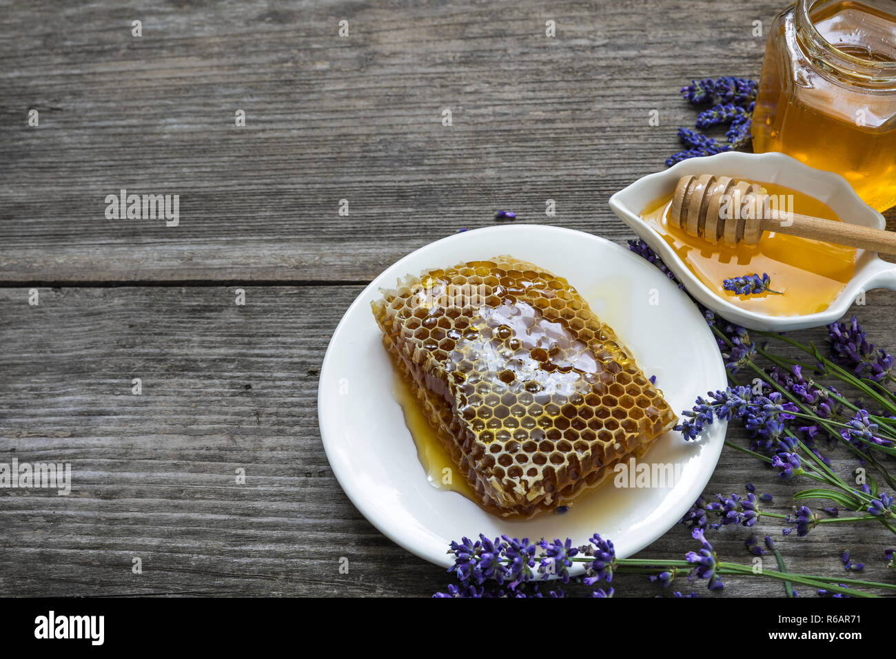 Honey with lavender flowers and honeycombs on rustic wooden table ...