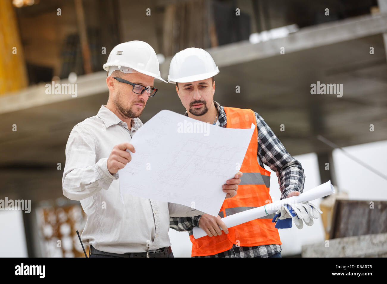 Male architect and developer discussing blueprints of an architect ...