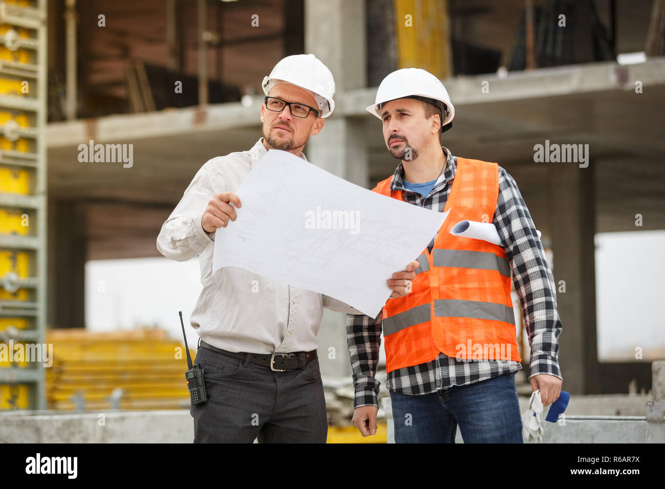 Male architect and developer discussing blueprints of an architect ...