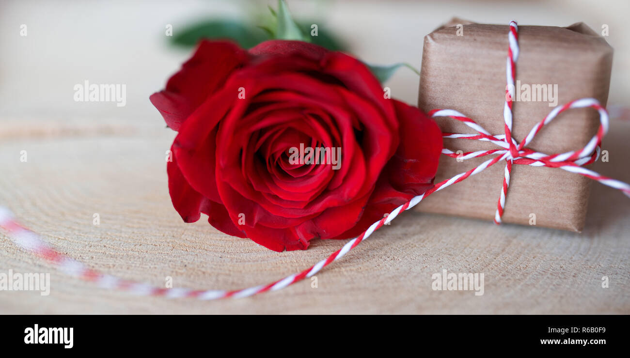 Red rose with gift on bright rustic wood Stock Photo - Alamy