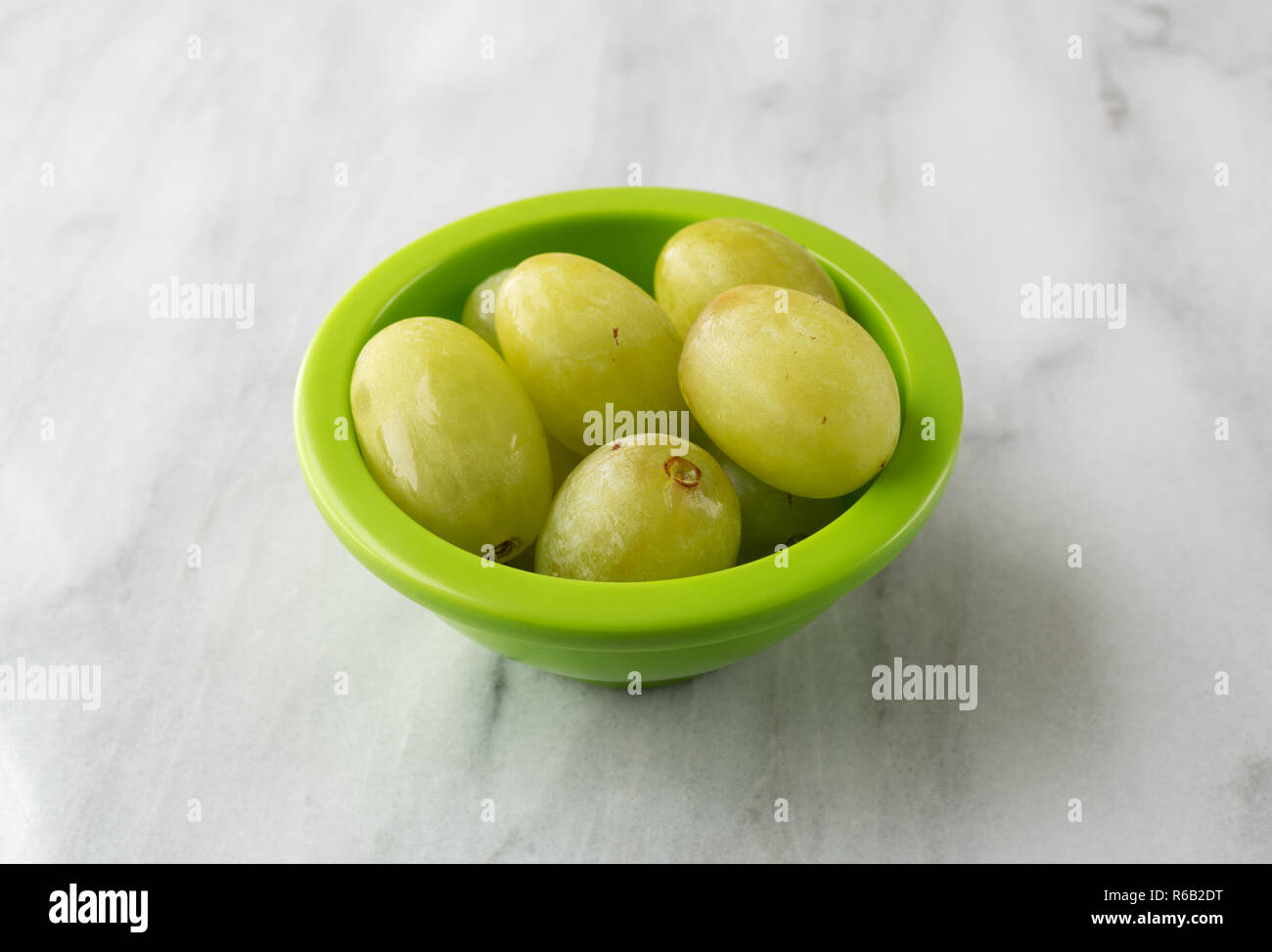 Side view of a serving of green grapes in a small bowl on a marble ...
