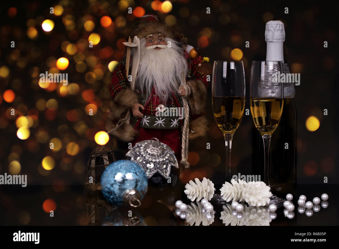 Two wine glasses with champagne, Santa Claus and Christmas ornaments on ...