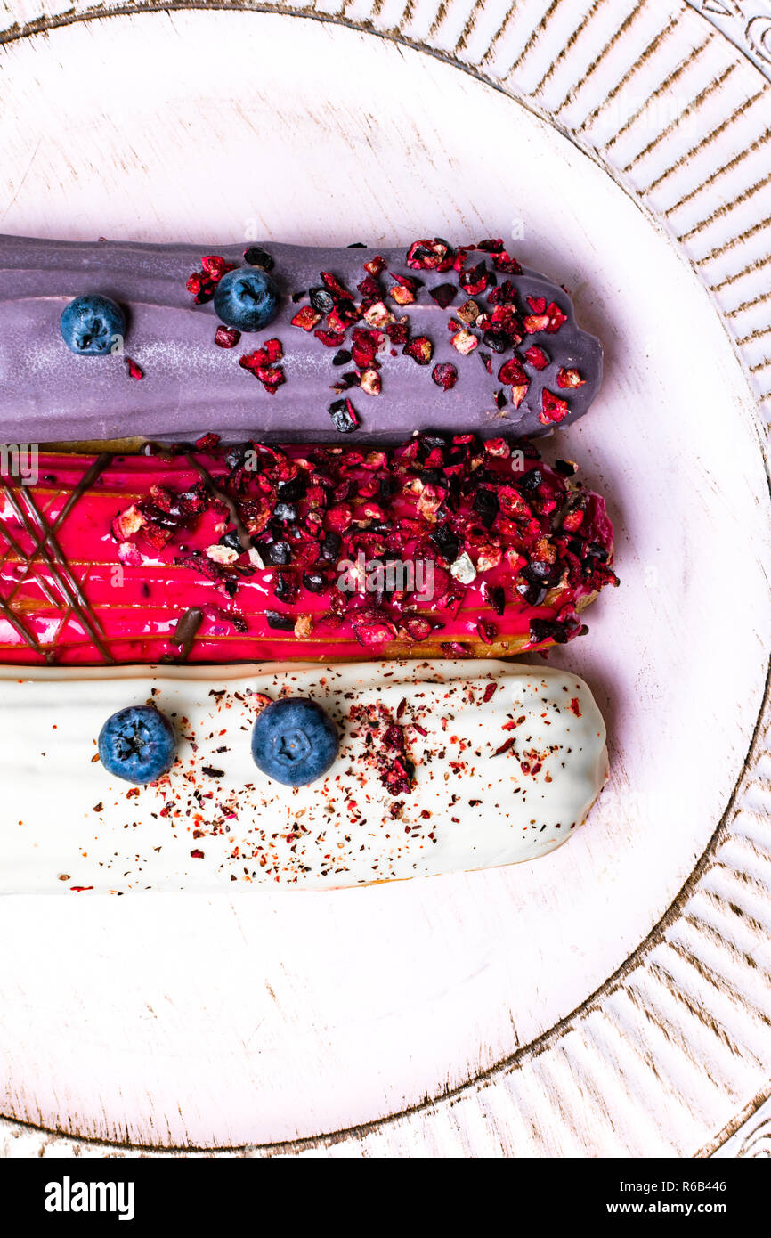 colorful eclairs red white violet with blueberry, raspberry, isolated ...