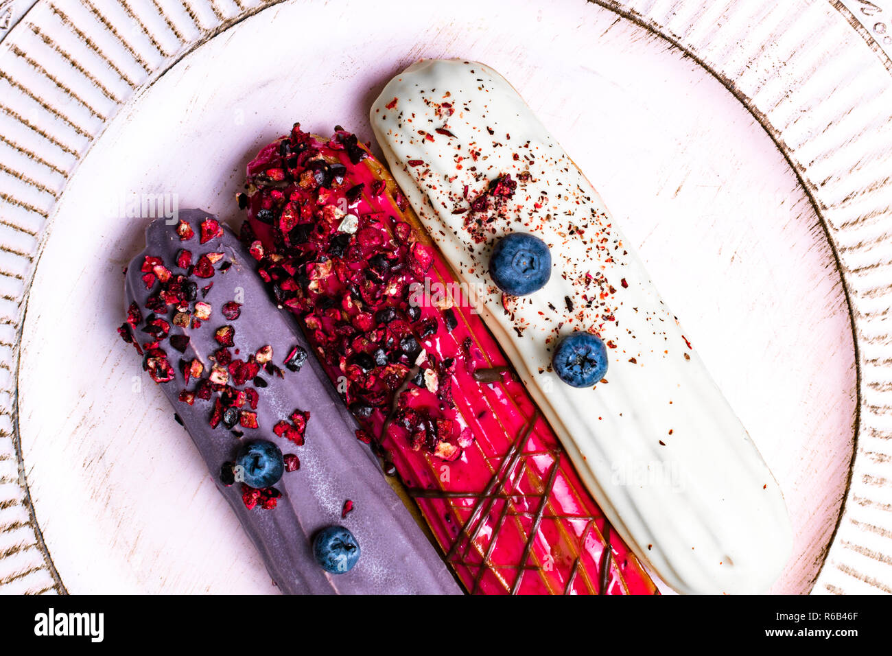 colorful eclairs red white violet with blueberry, raspberry, isolated ...