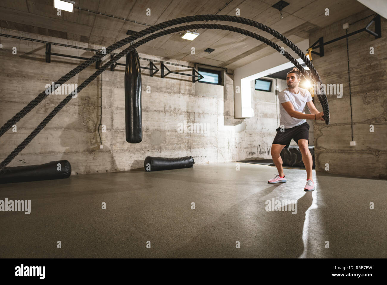 Young man doing strength training using heavy ropes at the gym. Athlete ...