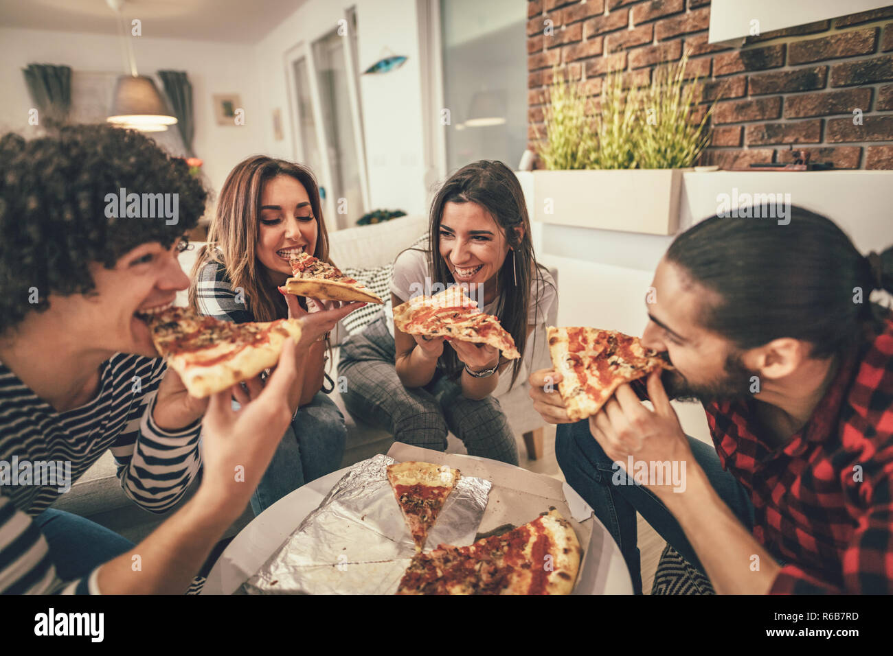Happy friends having fun while eating pizza. They have great weekend in ...