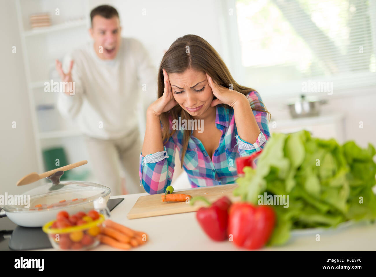 Young couple arguing in the domestic kitchen. Upset woman sitting and ...