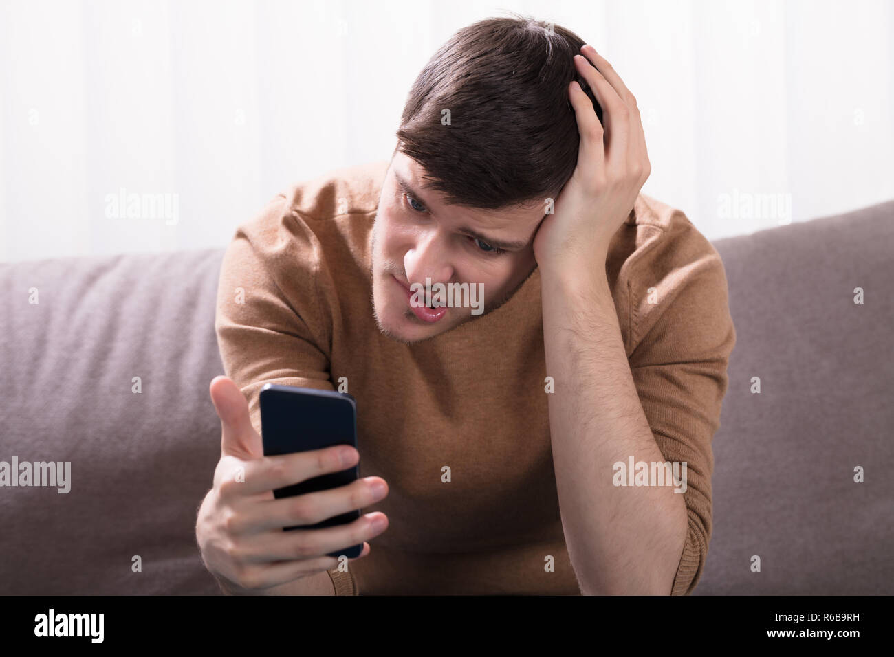 Shocked Man Looking At Smartphone Stock Photo - Alamy