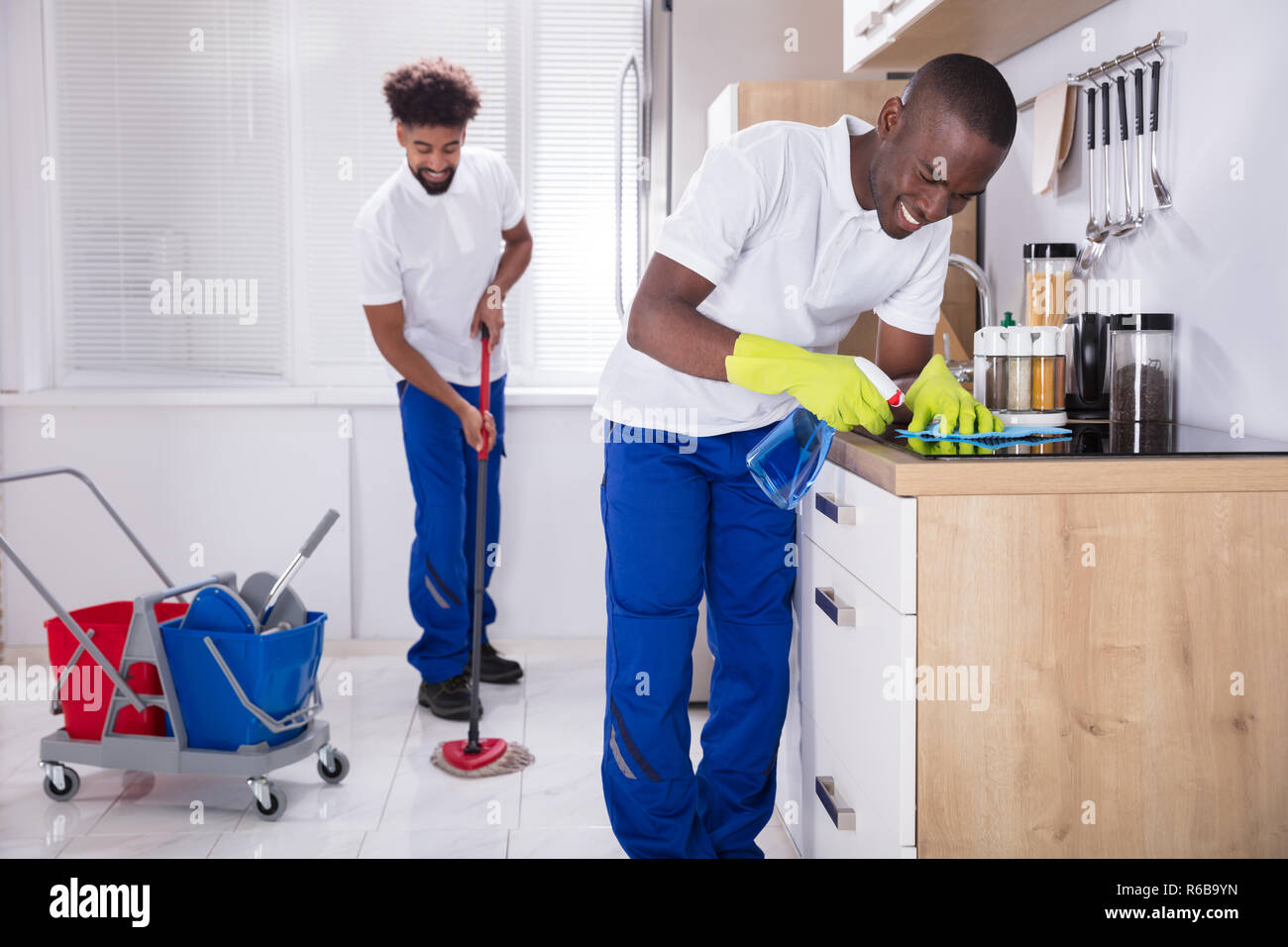 Smiling Two Young Male Janitor Cleaning The Kitchen Stock Photo - Alamy