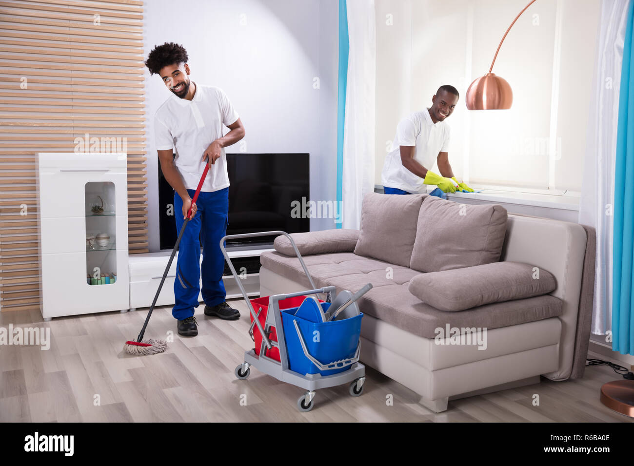 Smiling Two Young Male Janitor Cleaning The Living Room Stock Photo - Alamy