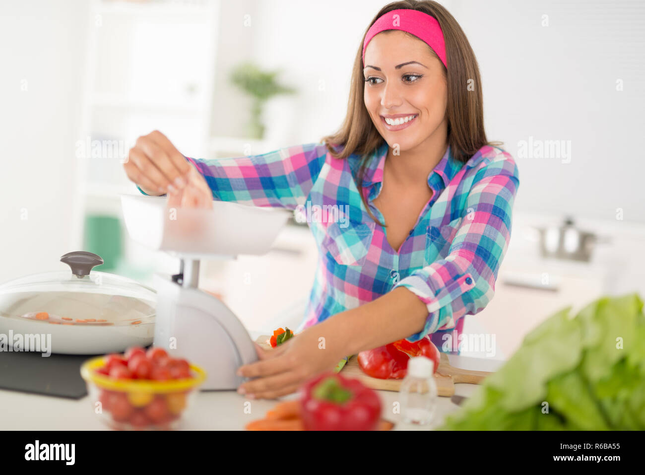 Beautiful young woman making healthy meal in the domestic kitchen. She ...
