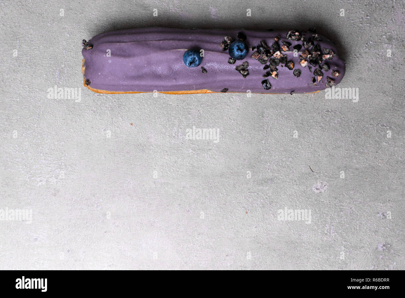 Traditional French dessert - eclair with purple cream icing and berries ...