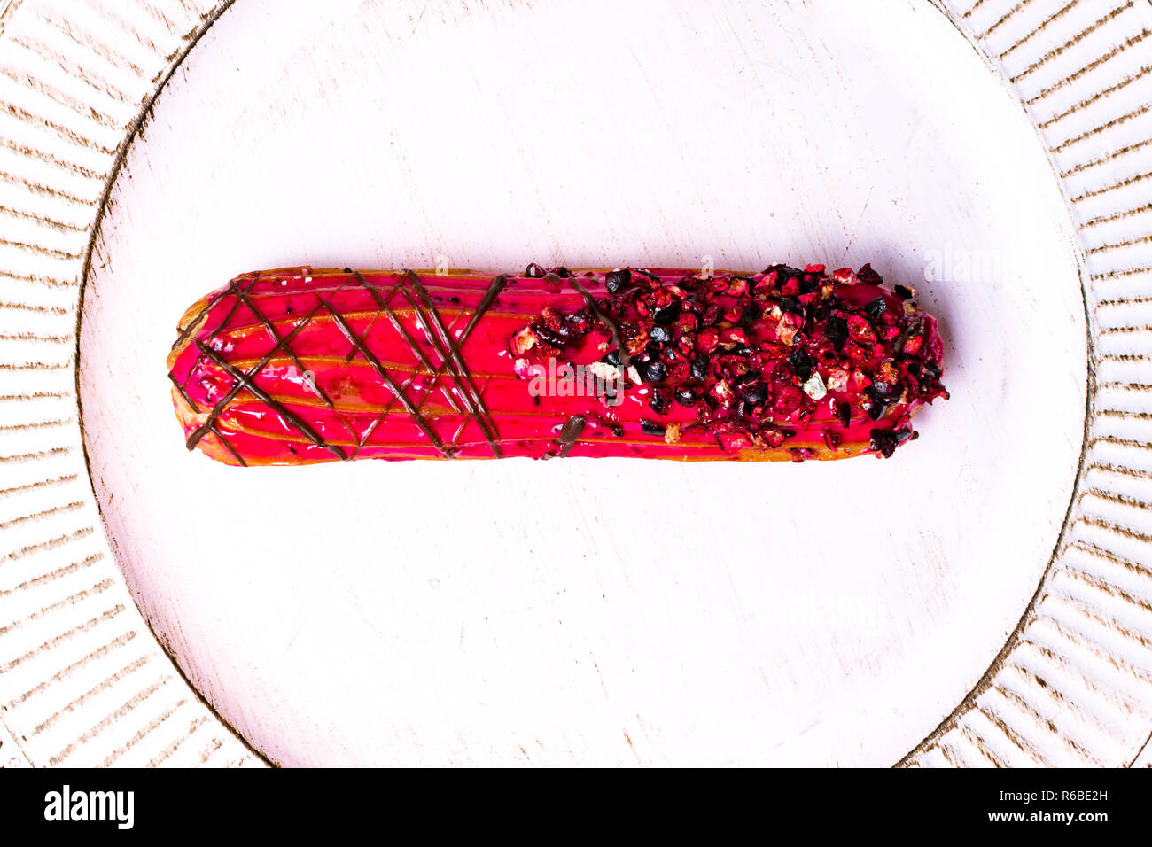 red eclair decorated with chocolate on white background. copy space ...
