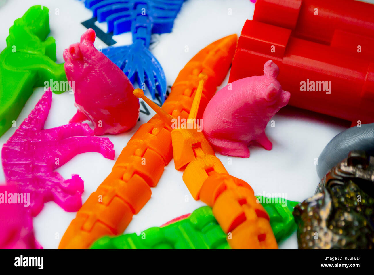 Many bright multi-colored objects printed on 3d printer lie on flat ...