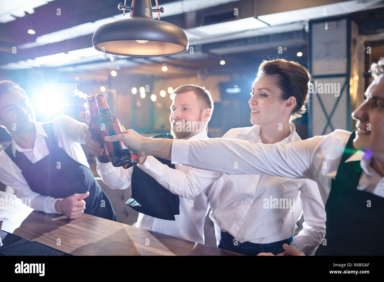 Group of cheerful excited waiting staff in uniform standing at bar ...