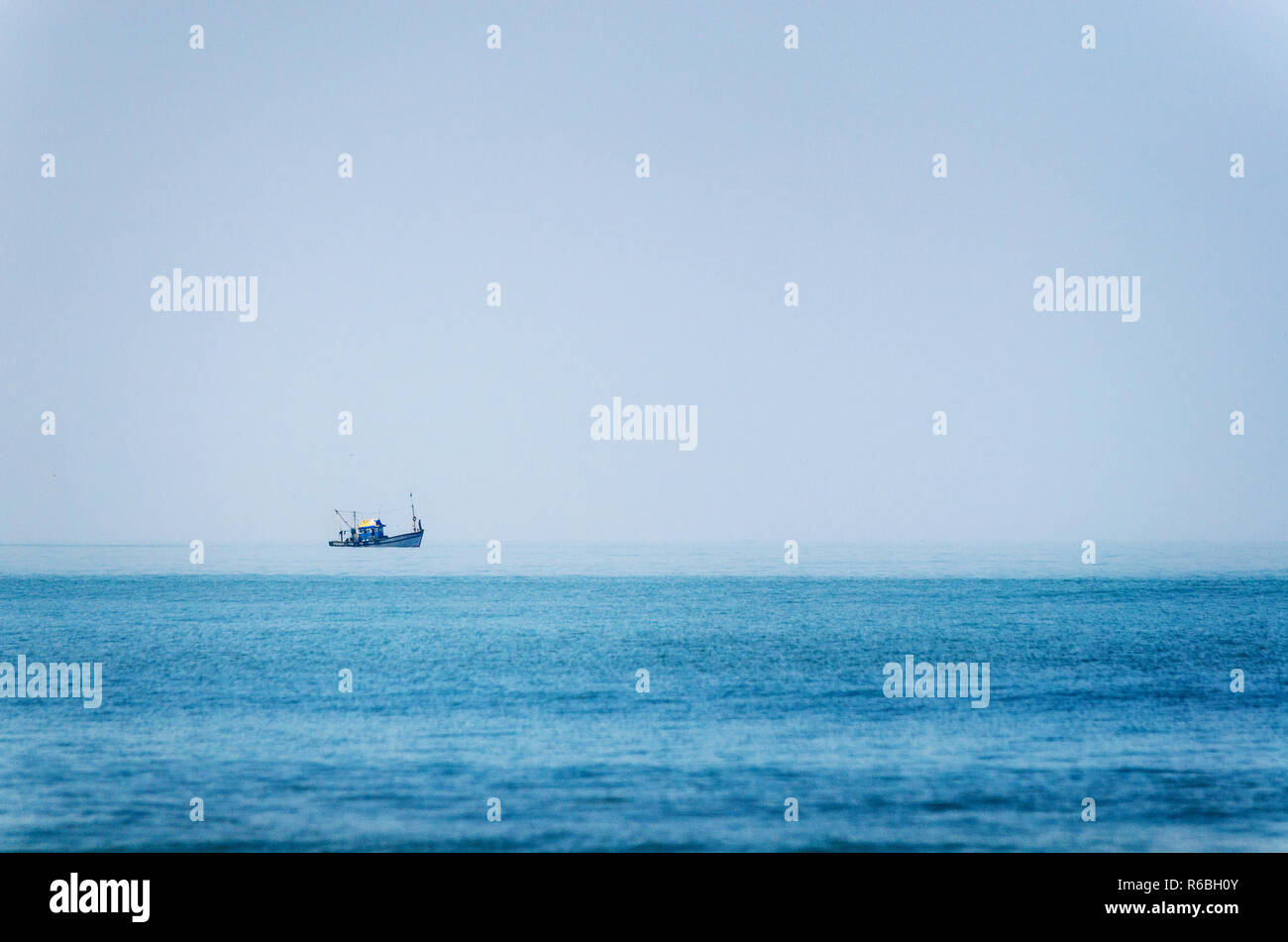 Lonely blue fishing trawler in the ocean in India Stock Photo - Alamy