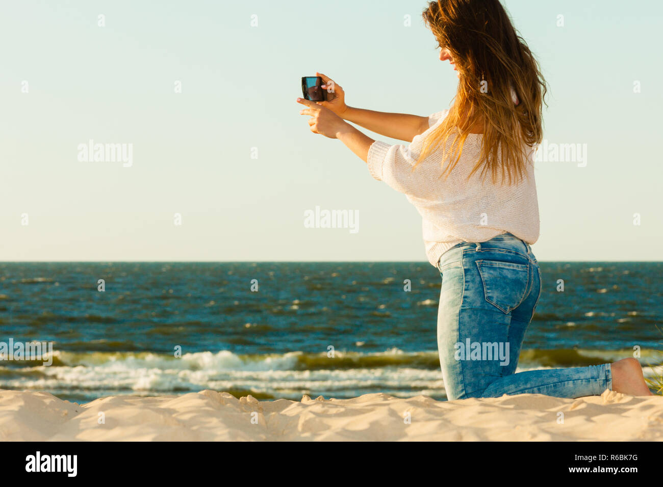 Fun with photography. Young smiling woman with mobile phone taking ...