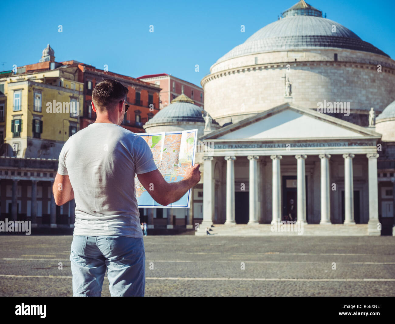 Handsome man holding a map against the background of the empty square ...
