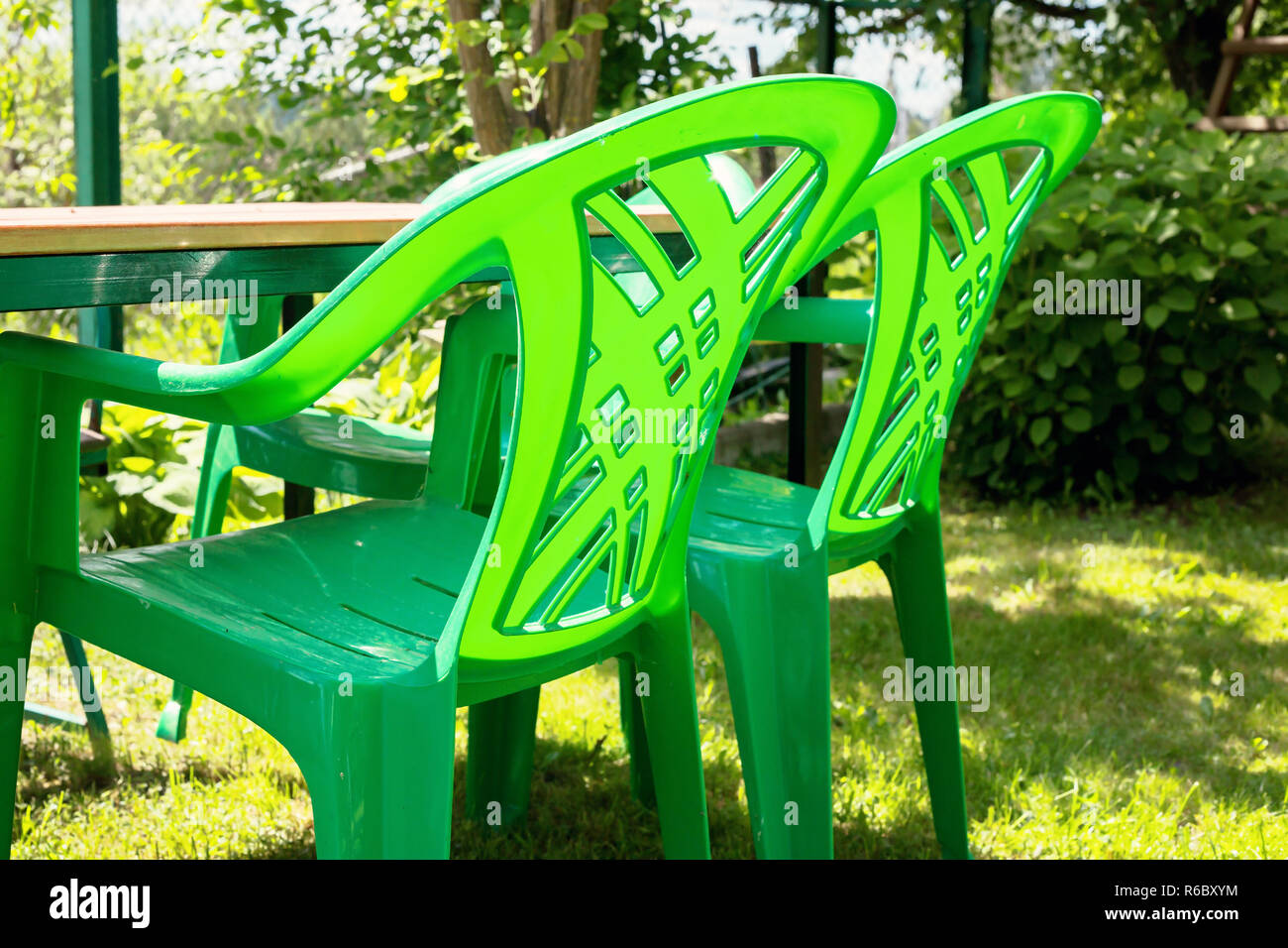 Plastic outdoor furniture in the sun. Green chairs lit by the sun on ...