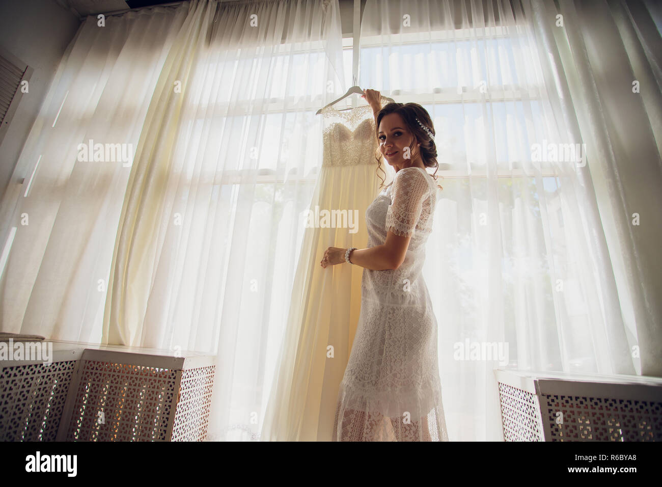 Pretty brunette bride in silk dressing gown and lacy veil holding ...