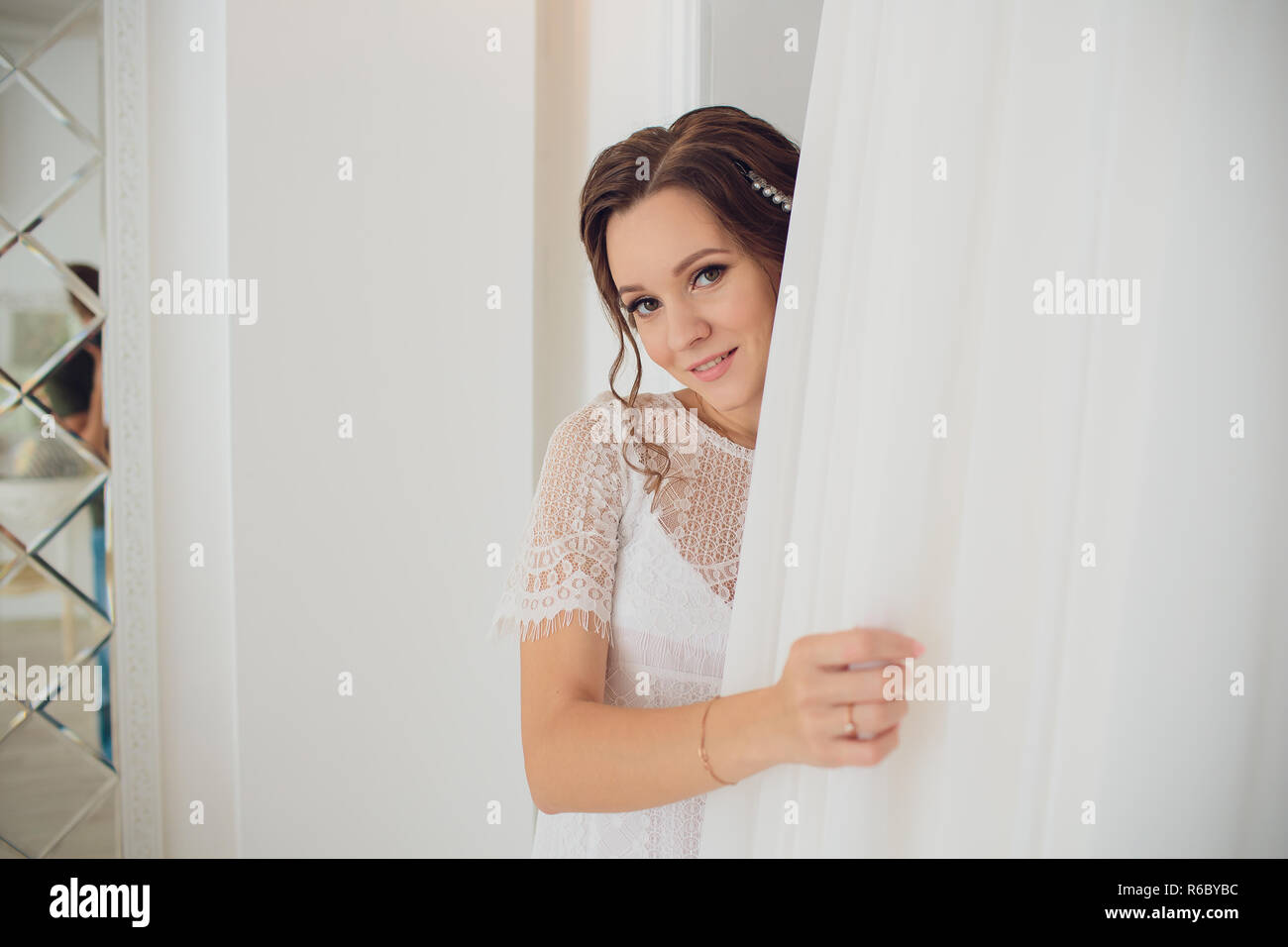 Pretty brunette bride in silk dressing gown and lacy veil holding ...