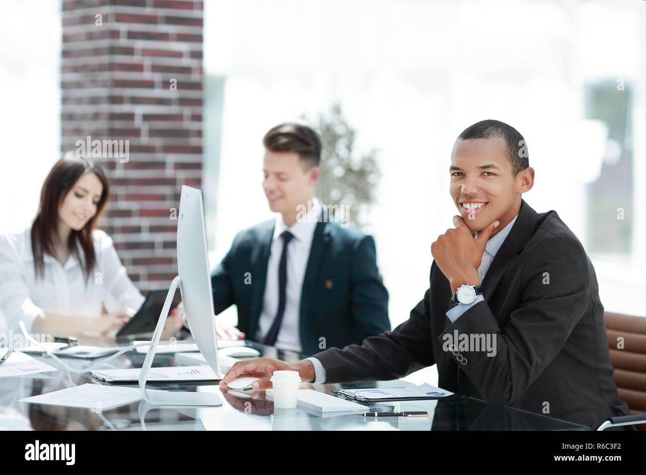 young businessman sitting behind a Desk in a modern office Stock Photo ...