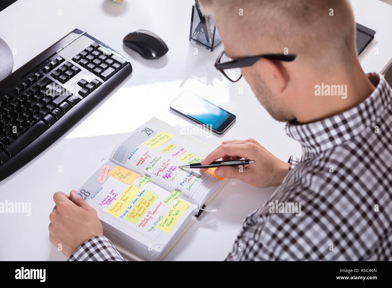 Businessperson With Mobile Phone Writing Schedule Stock Photo - Alamy