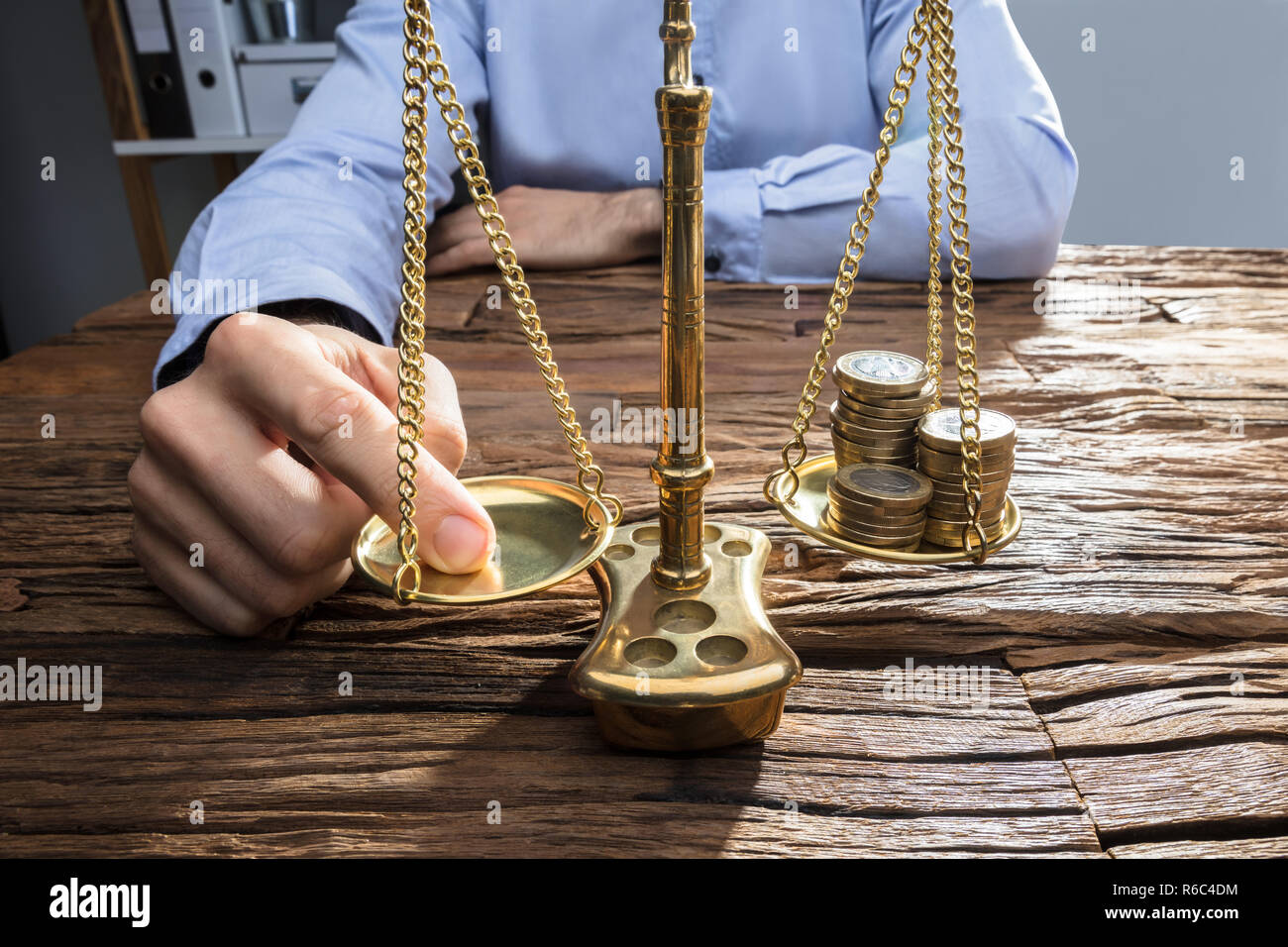 Businessperson Balancing Coins On Justice Scale With His Finger Stock ...