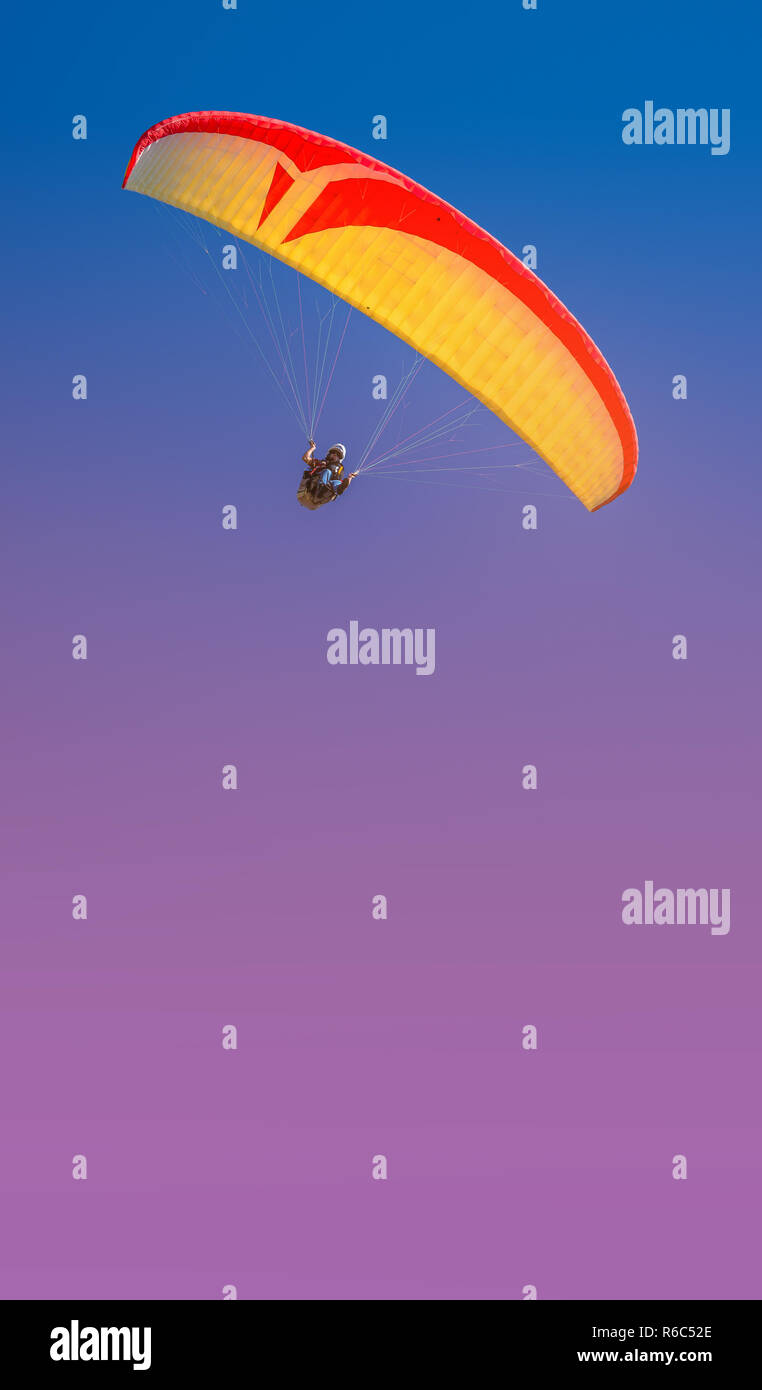 Beautiful yellow and red paraglider flying in colorful sky, paste space ...