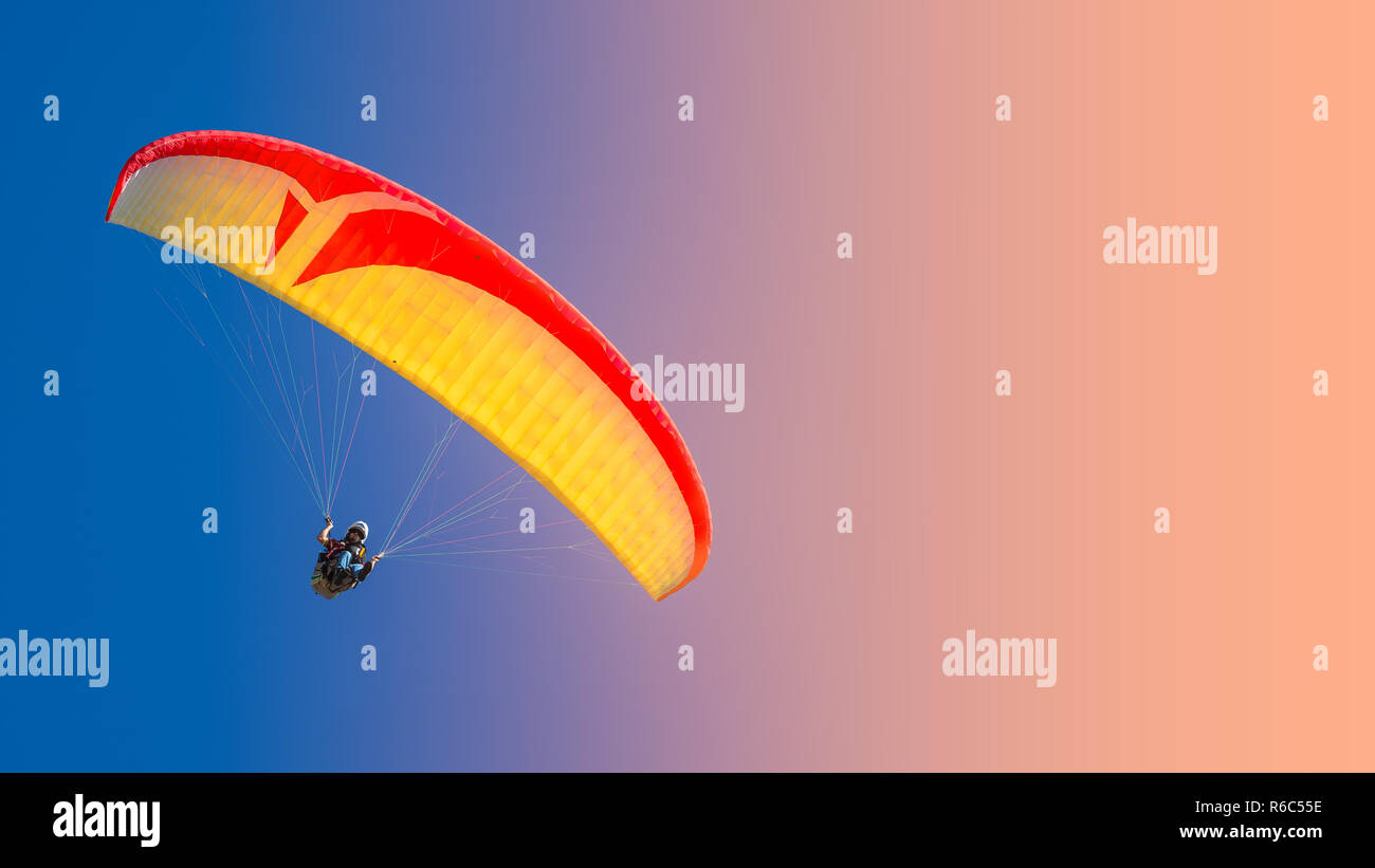 Beautiful yellow and red paraglider flying in colorful sky, paste space ...