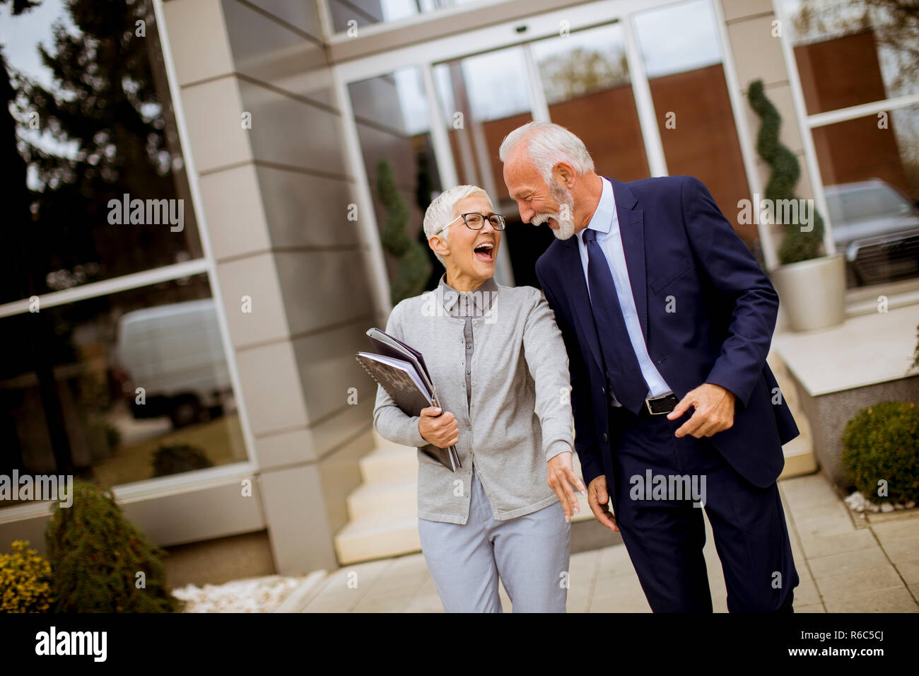 Senior businesspeople standing and talking outdoor office building ...