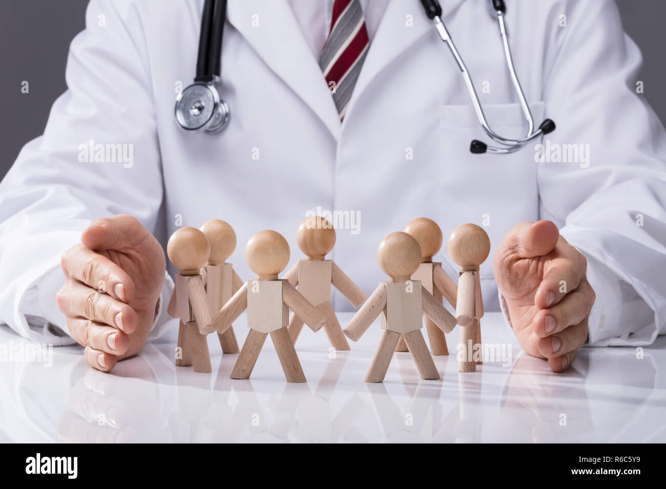 Doctor Protecting Wooden Figures Stock Photo - Alamy