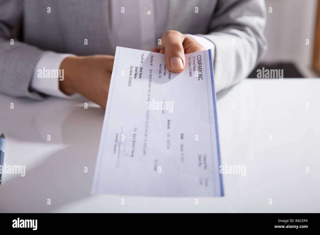 Businessperson Giving Cheque In Office Stock Photo - Alamy