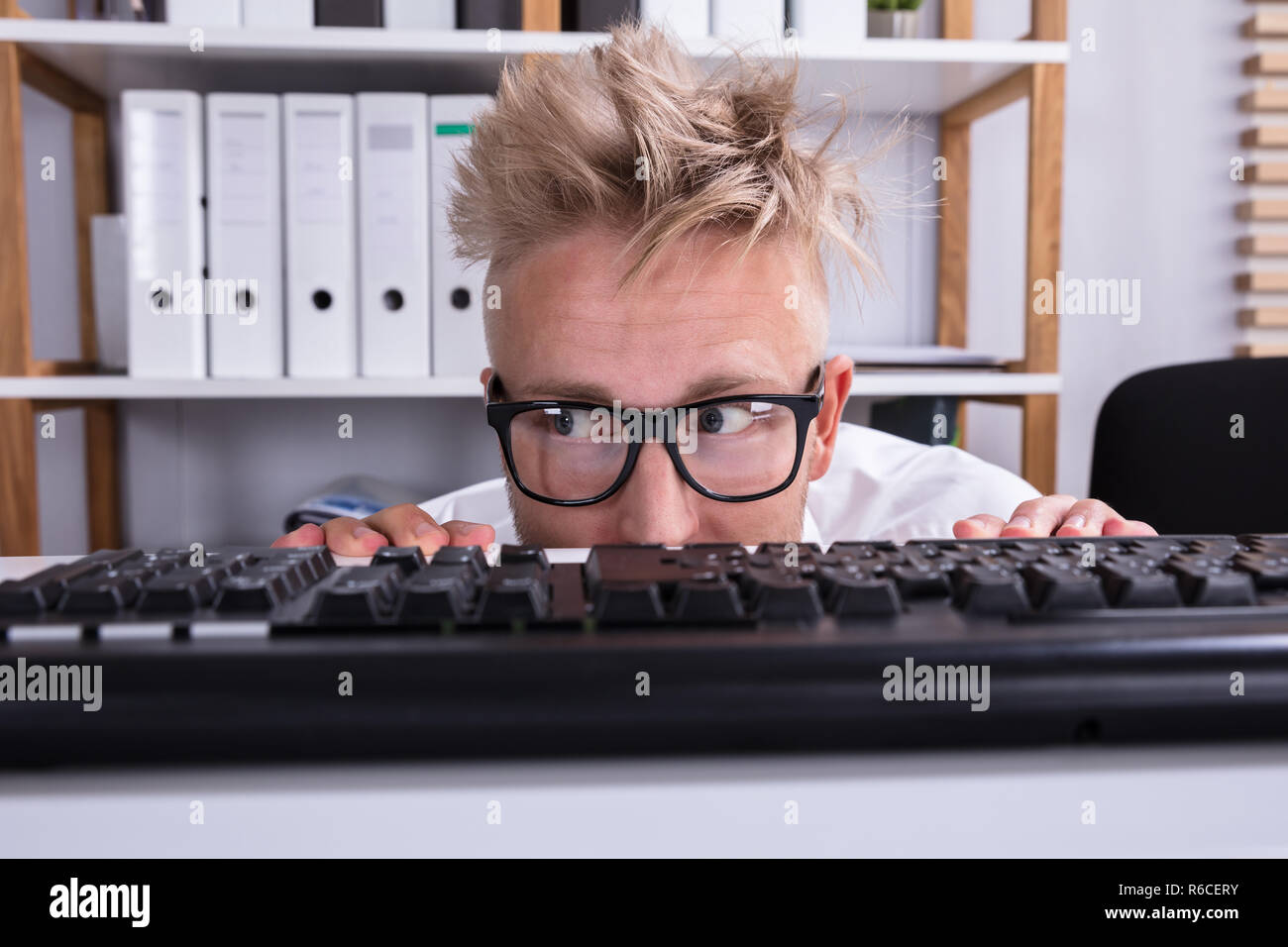 Funny Businessman Hiding Behind Desk Stock Photo - Alamy