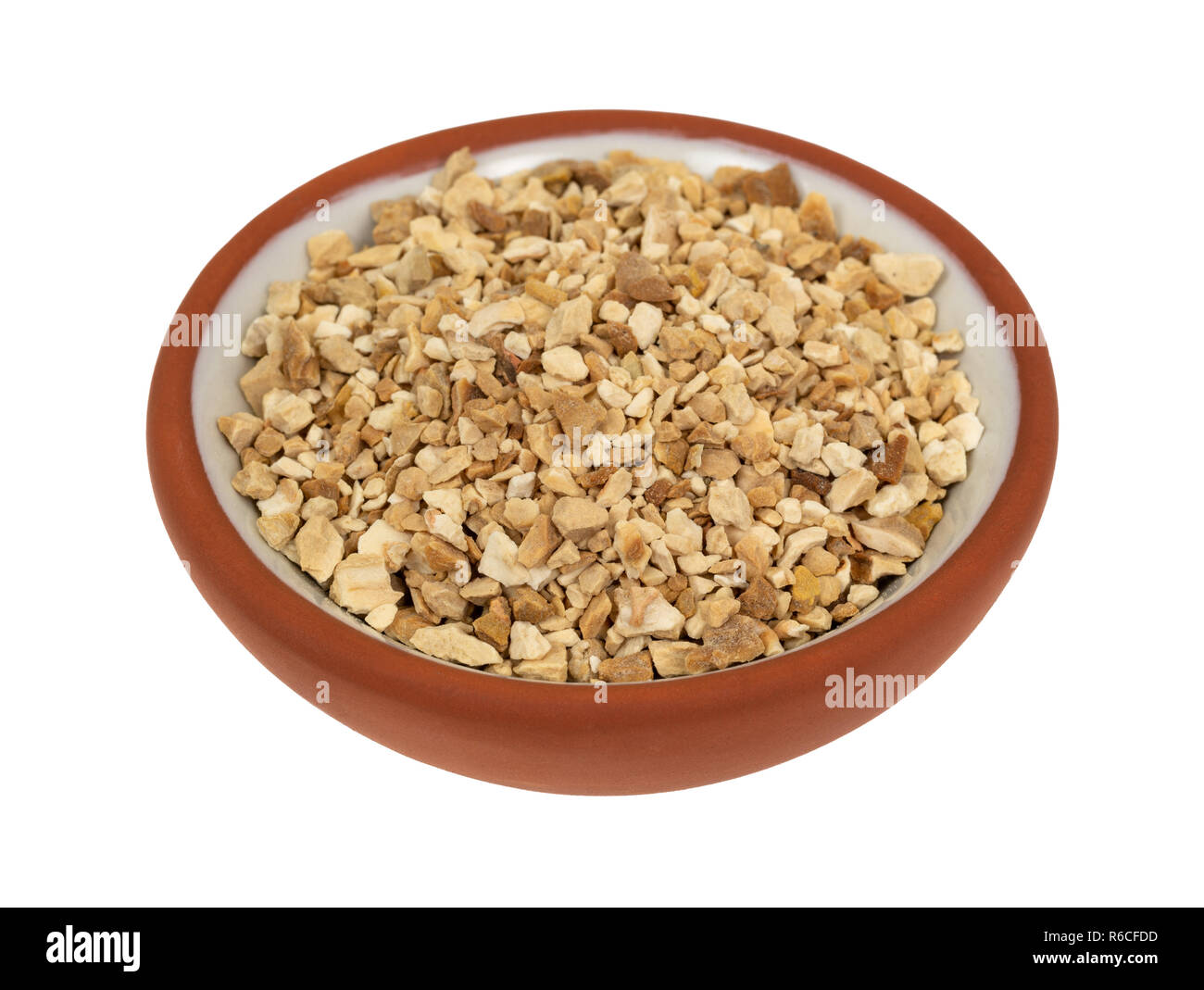 Side view of cut orris root in a small bowl isolated on a white ...