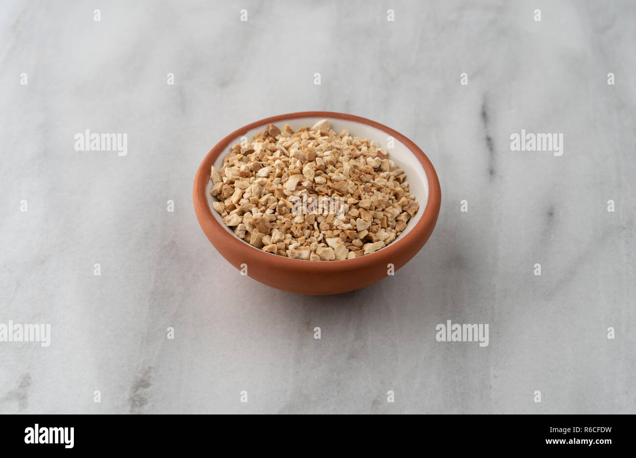 Side view of a small bowl of cut orris root on a gray marble counter ...