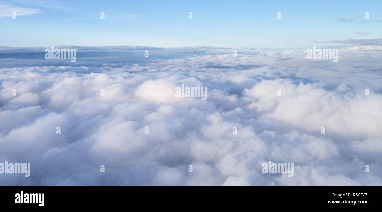 Cloudscape above cloud level view. Blue clear sky over gray clouds ...